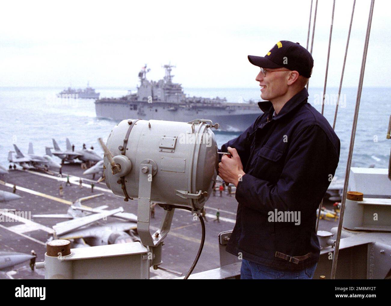 Signalman 3rd Class James Hage signals another ship from the aircraft ...