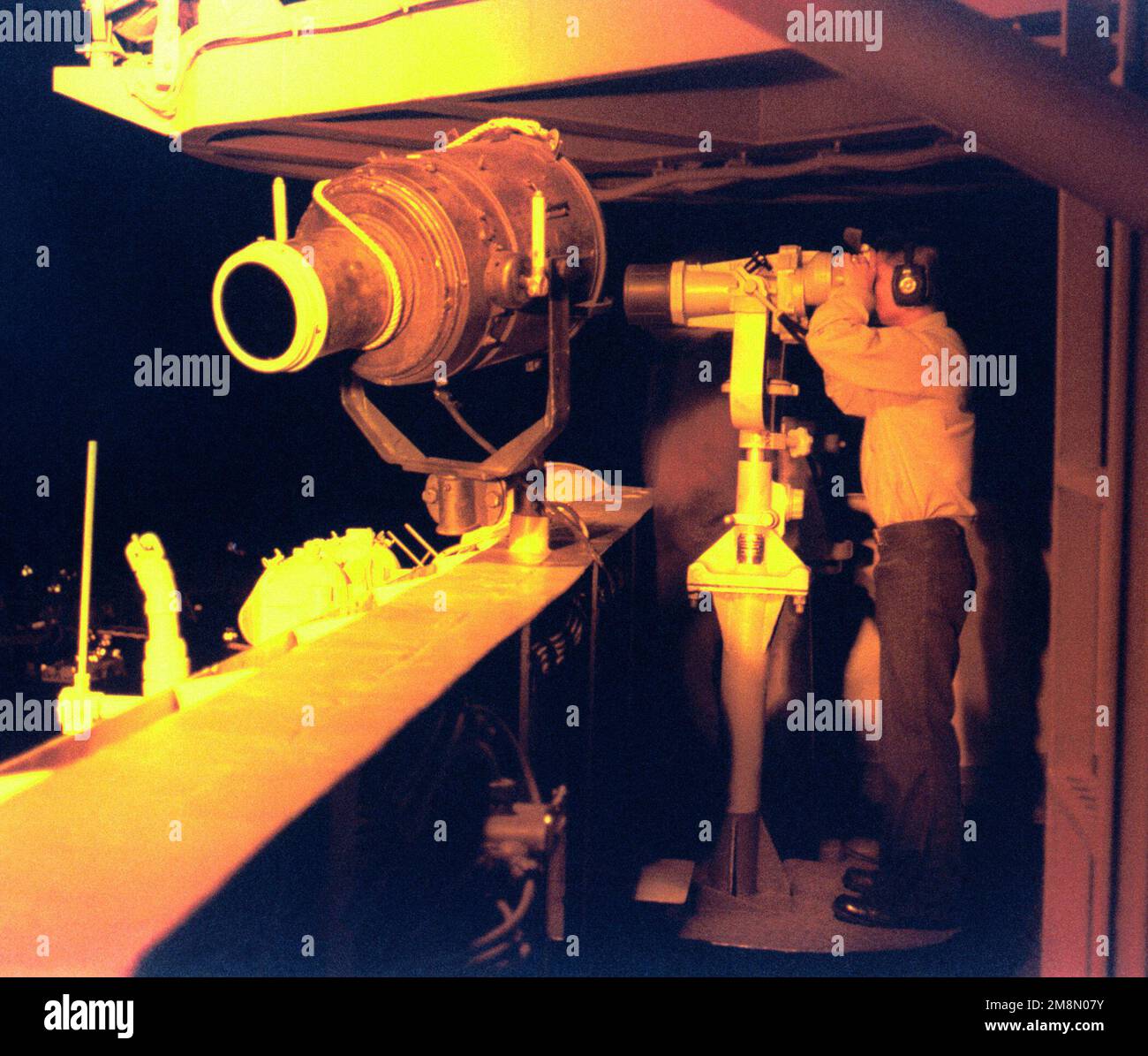 Under the amber lights of the ships superstructure, Signalman 3rd Class ...