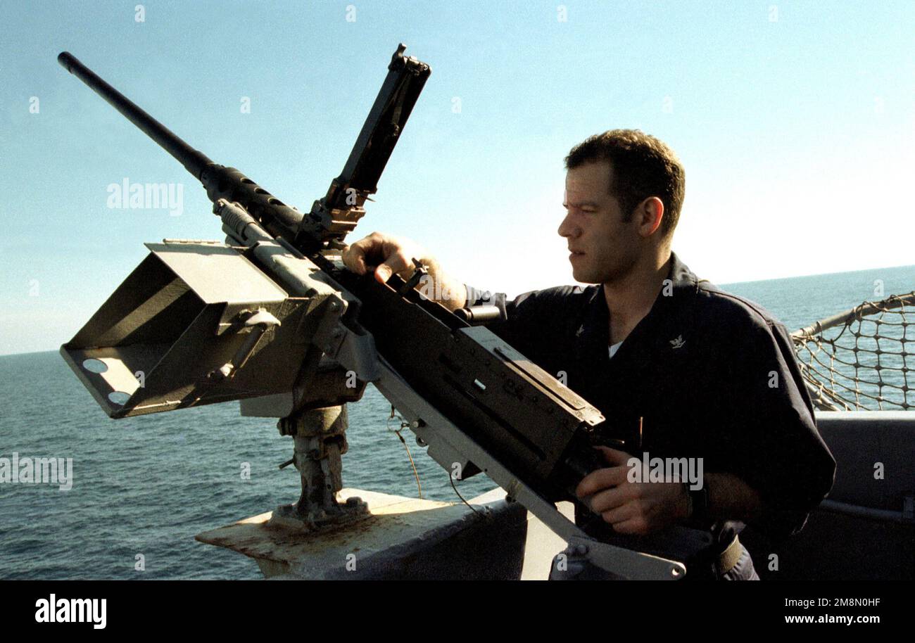 Aviation Ordnanceman 3rd Class John Dahl checks a .50-caliber mounted ...