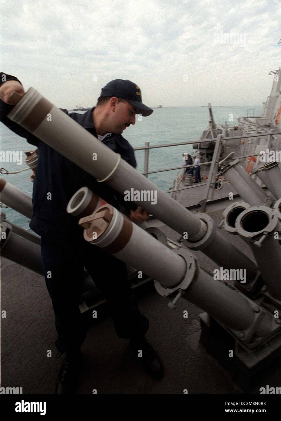 A crew member on the USS CARNEY (DDG 64) loads "chaff" canisters in ...