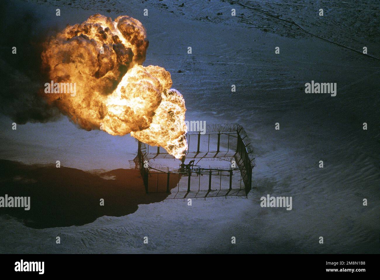 An oil well burns out of control, darkening the sky with smoke, after ...