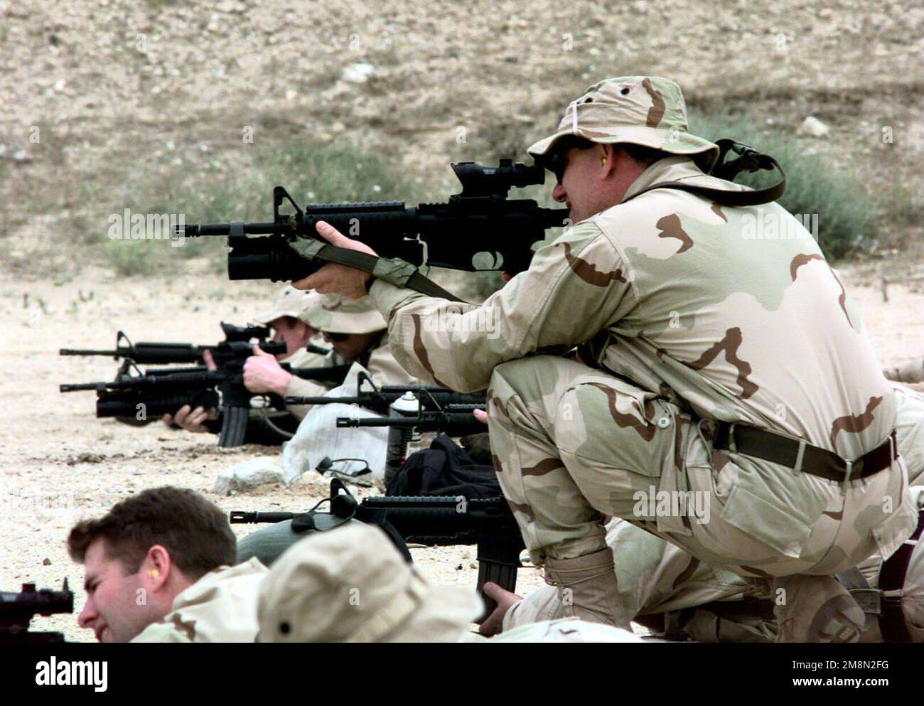 A US Navy SEAL (Squatting), from SEAL Team 8, uses the scope on his ...