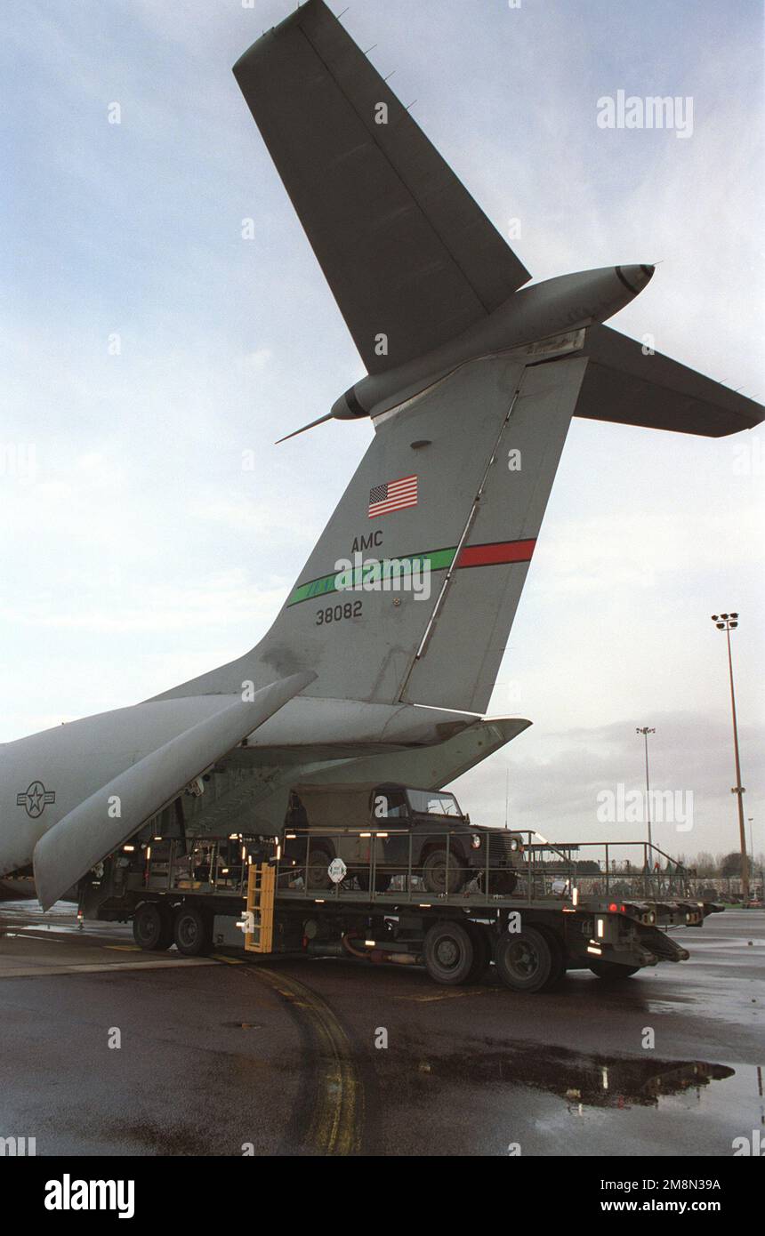 Cargo is being moved to the C-141 Starlifter. A team member drives the ...