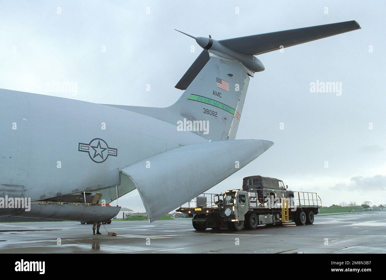 Cargo is being moved to the C-141 Starlifter. A team member drives the ...