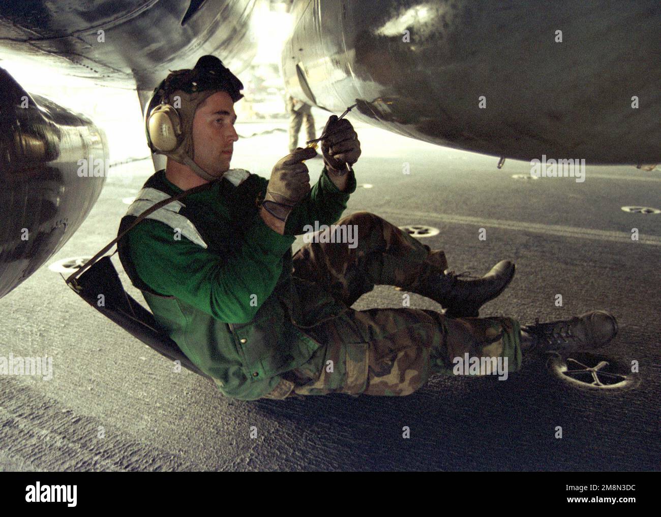 Photographer's Mate 3rd Class (PH3) Jason Stiles removes a panel from ...