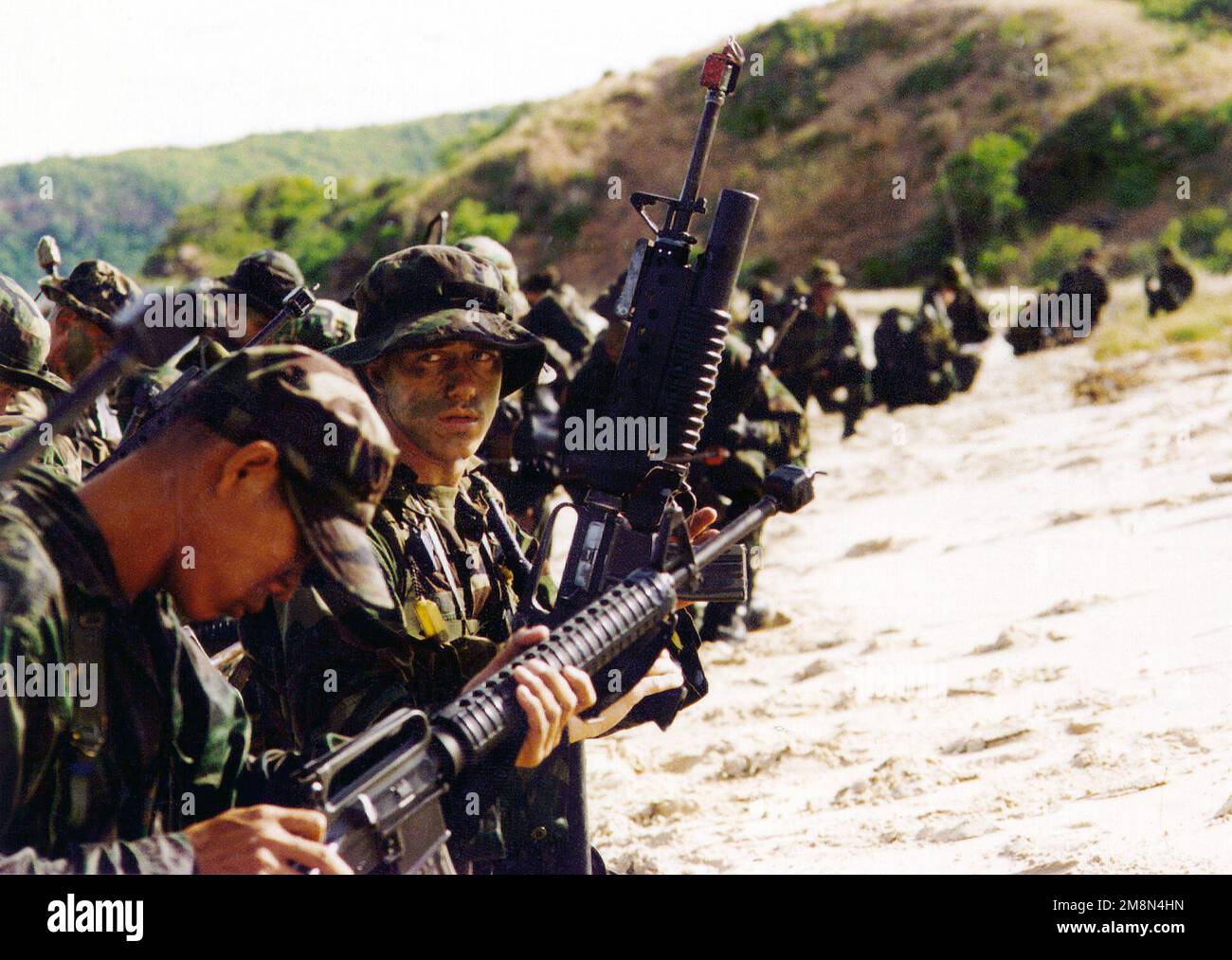 Marines, armed with M16 rifles, assemble on the beach before heading ...