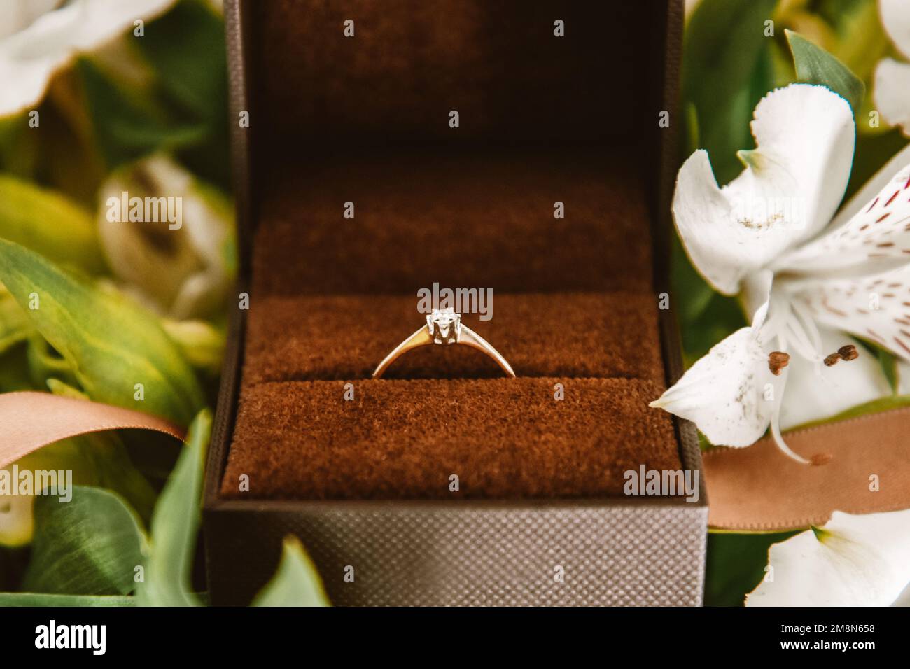 Wedding ring in a box close-up, gold ring with a diamond in flowers ...