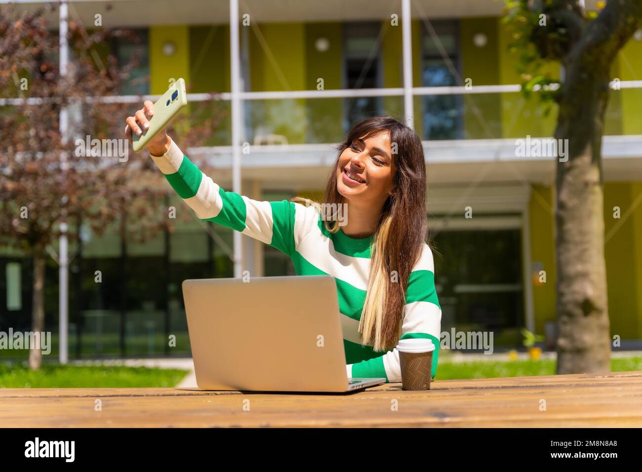 Portrait of a caucasian girl working with a computer in nature, taking ...