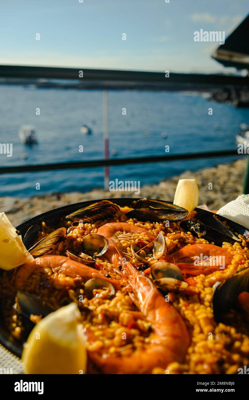 Paella with a huge iron spoon, shrimp and mussels, lemon. On the ...