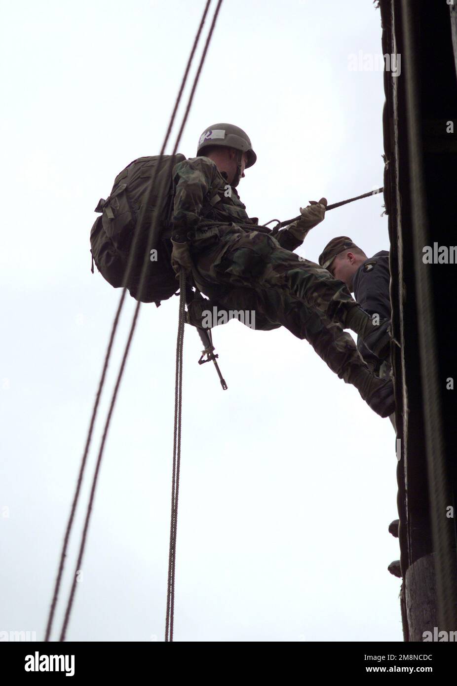 1LT Jones, carrying a full field pack and an M-16, prepares to rappel ...