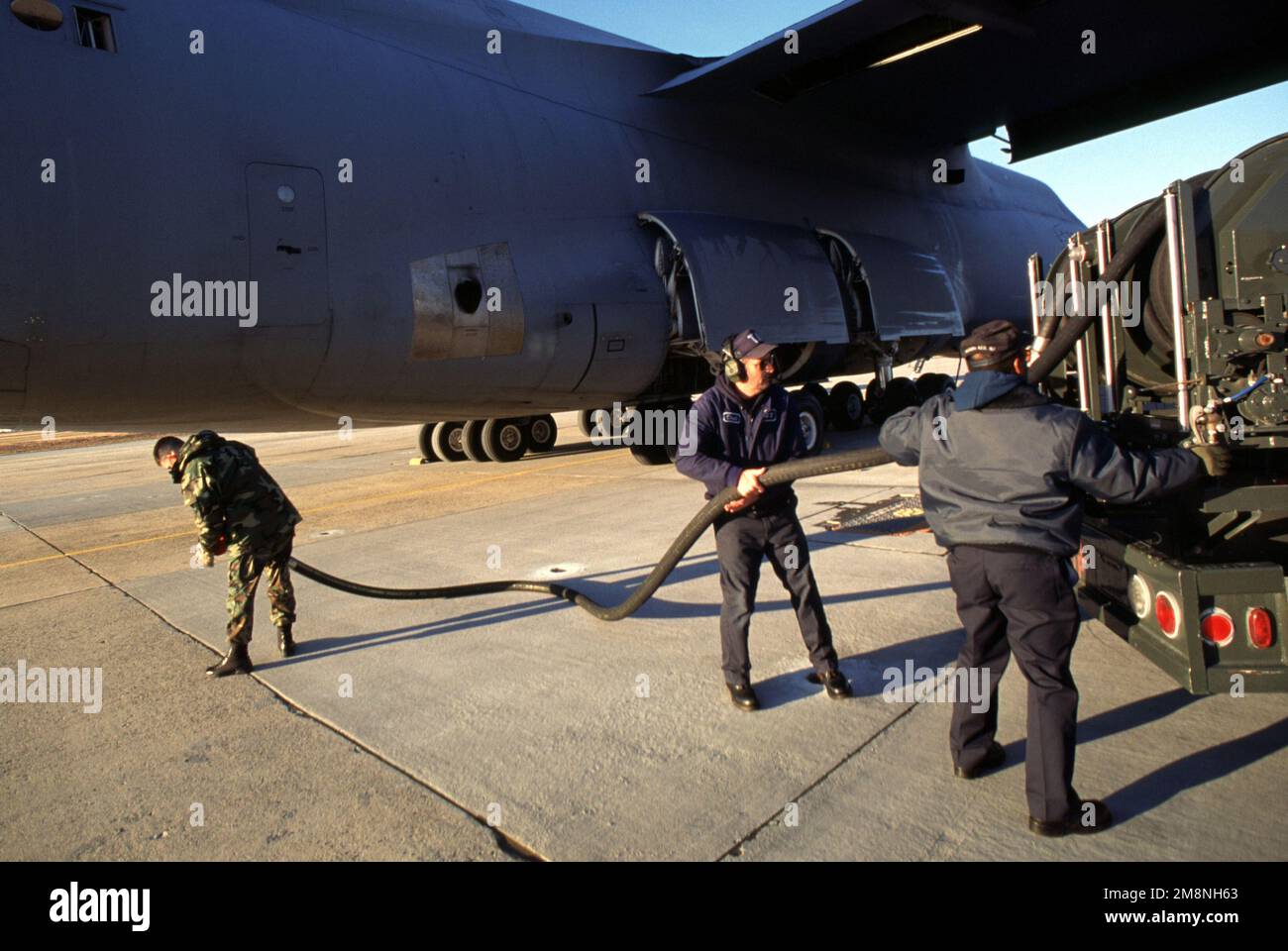 USAF and civilian ground crew personnel prepare to fuel a C-5 Galaxy ...