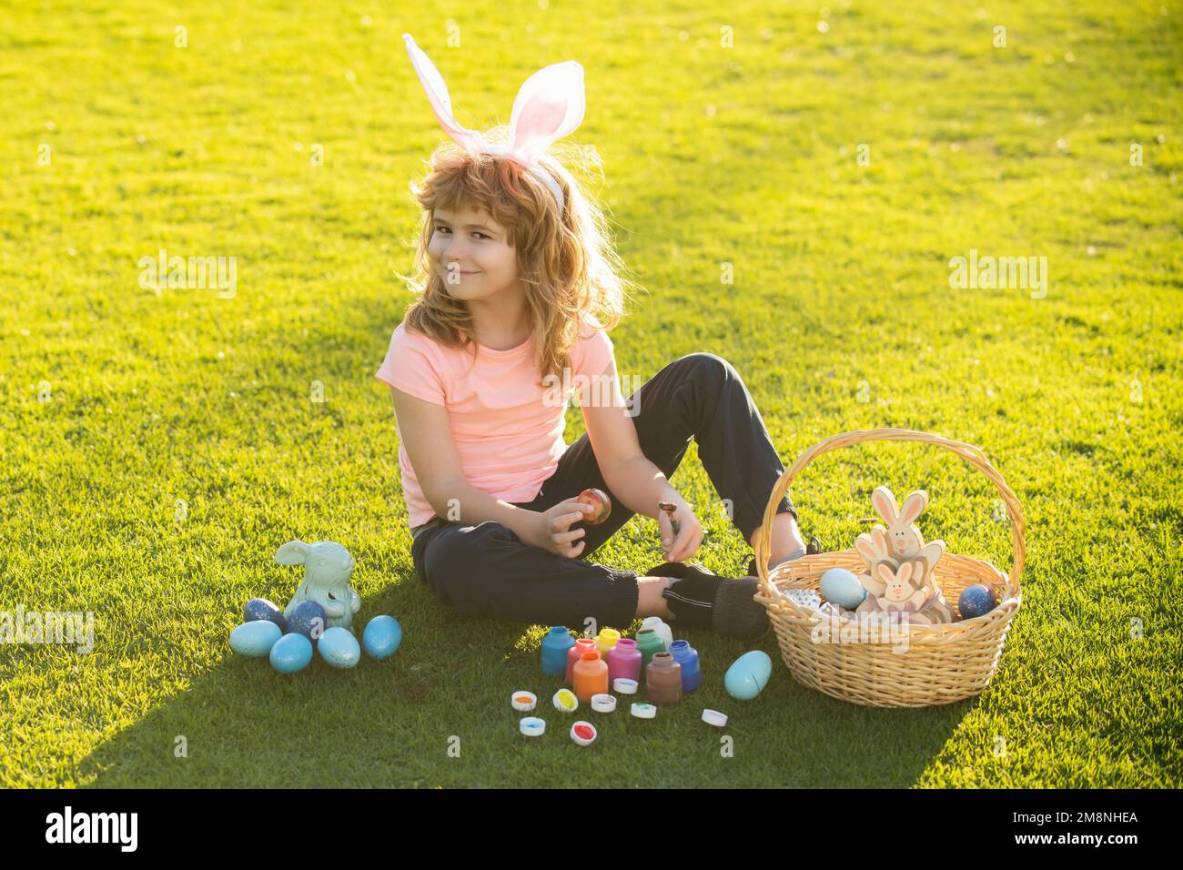 Easter bunny kids. Child boy in bunny Easter ears painting eggs. Cute ...