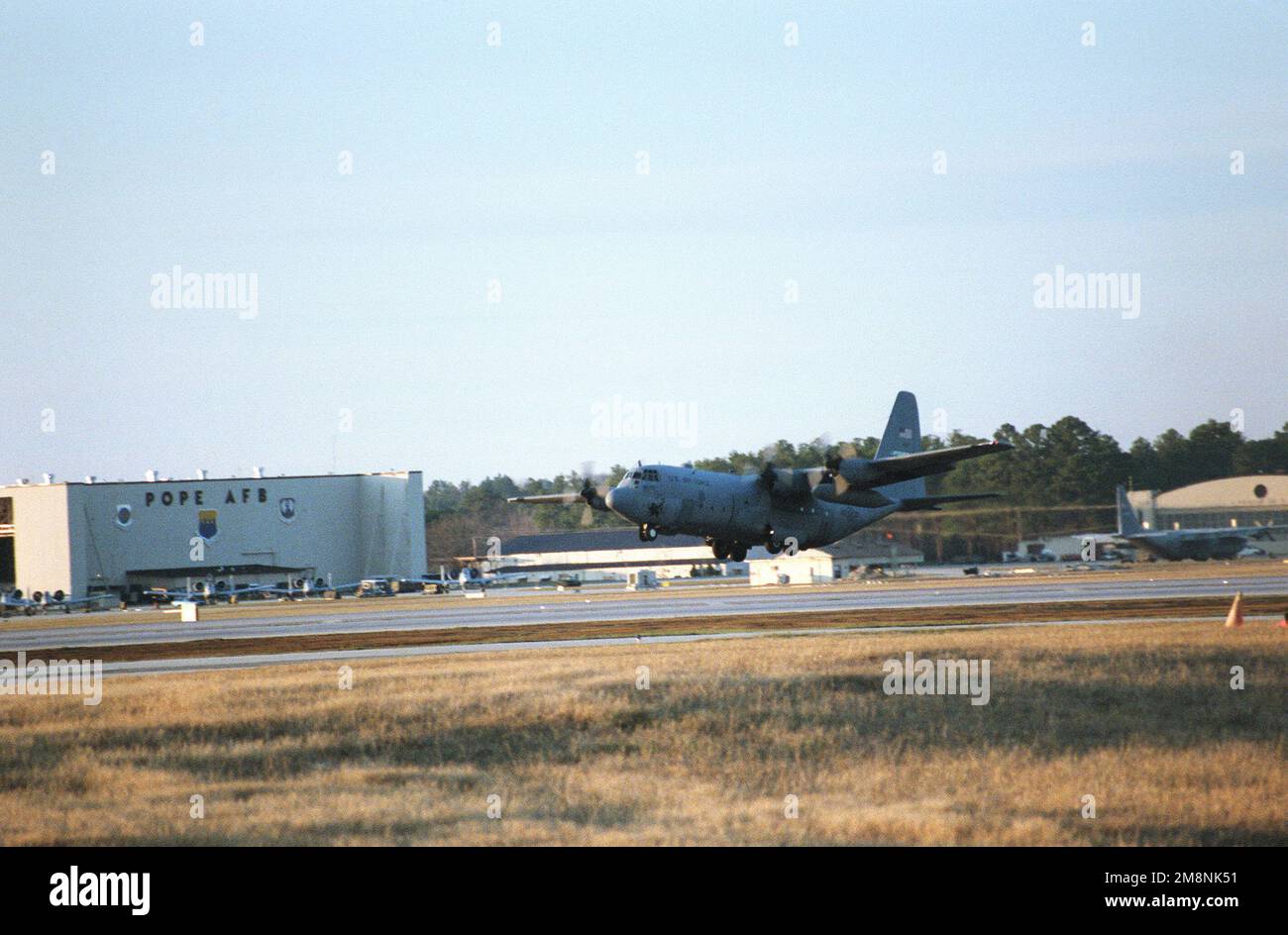 A C-130E of the 43rd Airlift Wing takes off into the setting sun ...