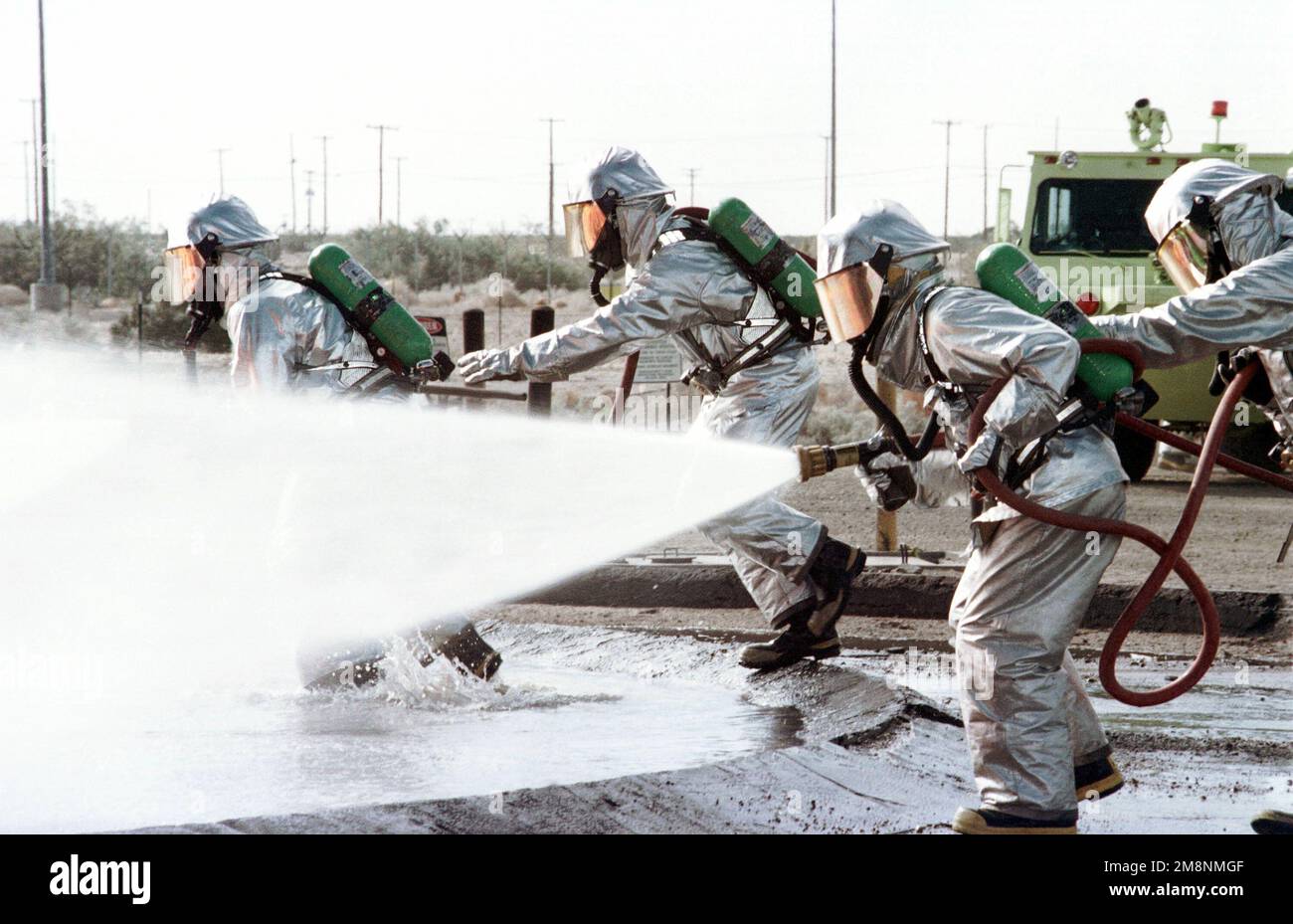 Members of a crash fire rescue team advance into a fire pit in order to ...