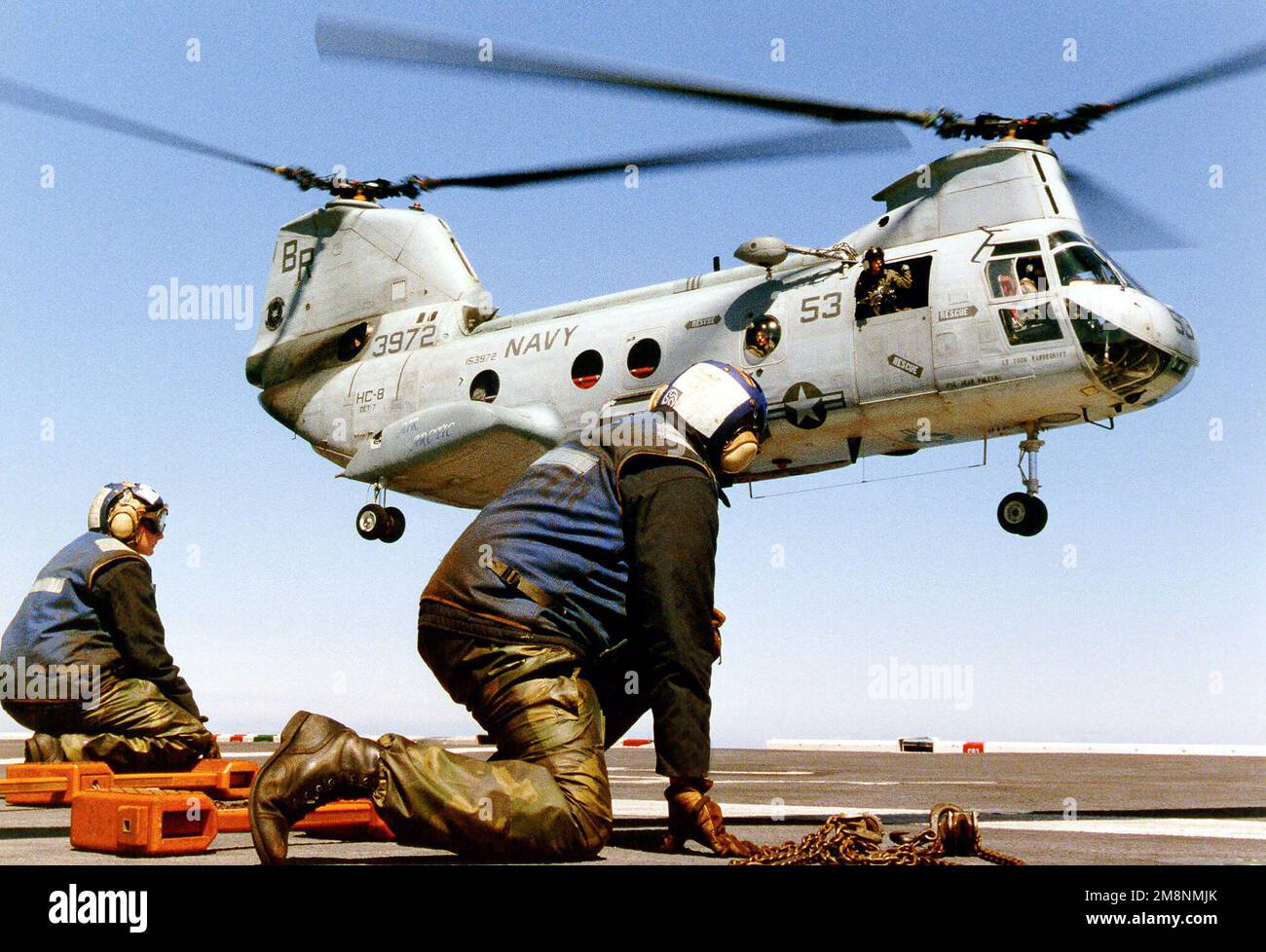 Flight deck crewmen prepare to chock and chain a UH-46D Helicopter from ...