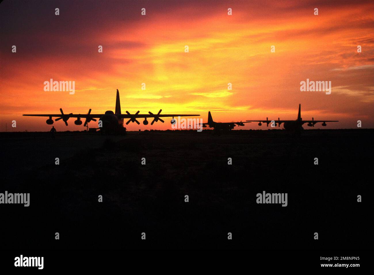 C-130 Hercules sit on the flightline during the evening sunset at Ali ...
