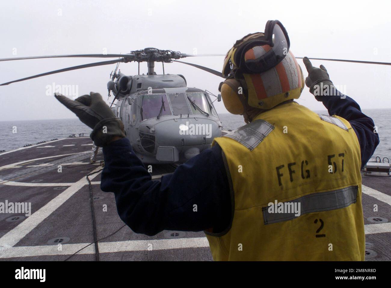 US Navy Boatswain's Mate 3rd Class Adrian Roble signals to the pilots ...