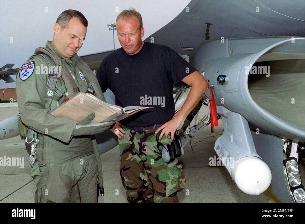 Pilot and crew chief review tech manual beside an F-16C, Block 52 ...
