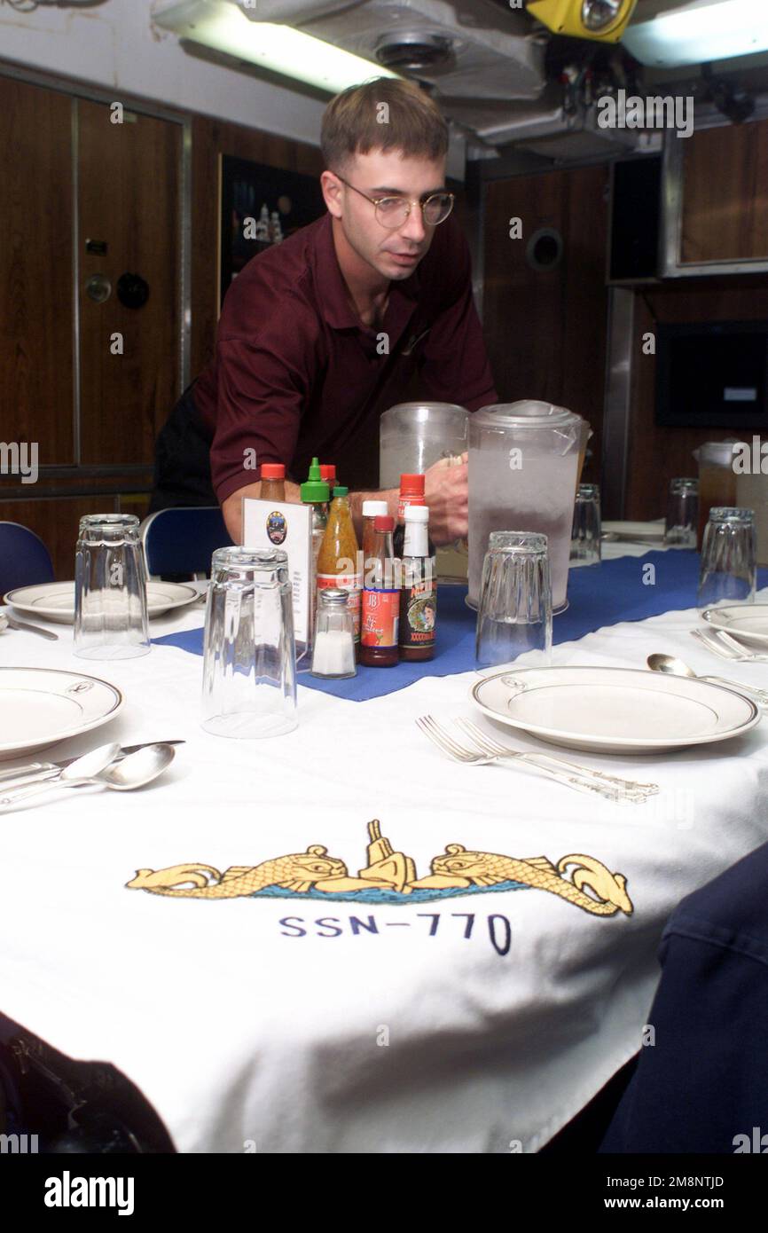 US Navy Mess SPECIALIST 3rd Class Eric Brown sets the dinner table in ...