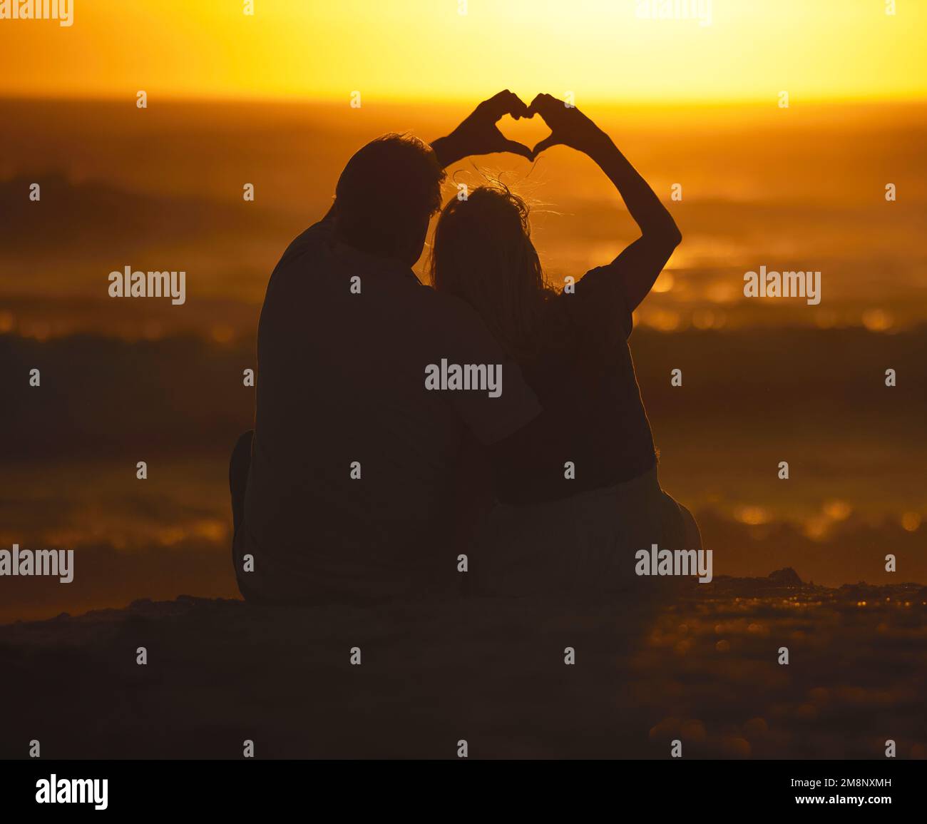 Back of a couple forming a heart with their hands. Loving mature couple ...