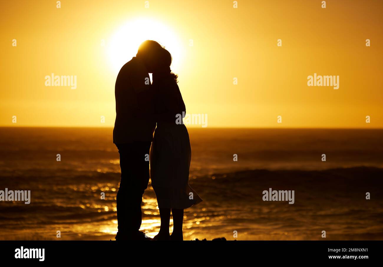 Mature couple bonding at sunset on the beach. Silhouette of senior ...