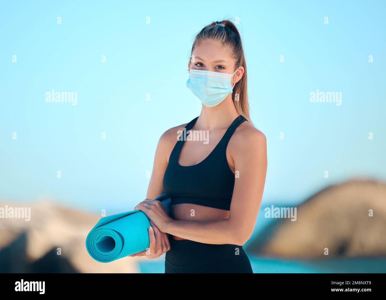 Beautiful woman doing yoga exercise while wearing a mask. Young female ...
