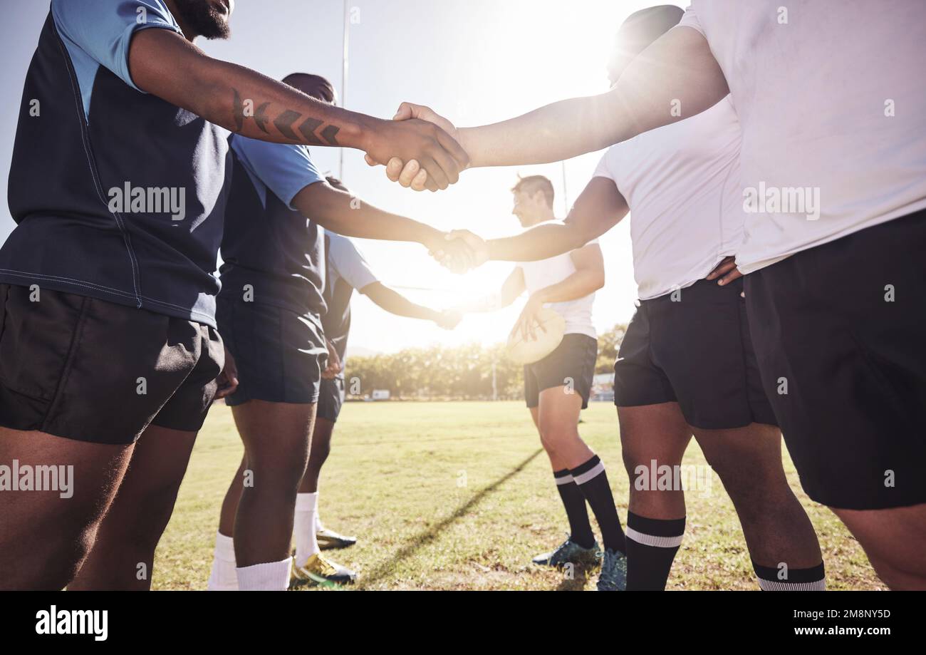 Two opponent rugby teams shaking hands before or after a match outside on a field. Rugby players ...