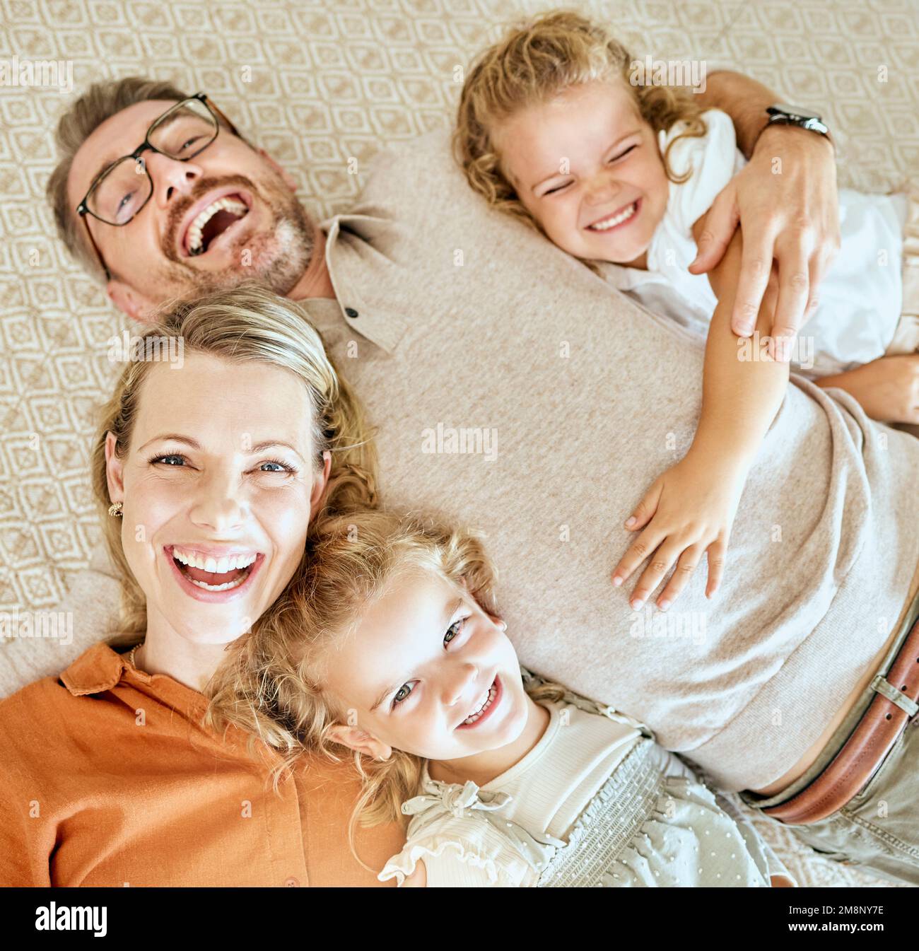 A happy Caucasian family of four lying in the living room at home ...