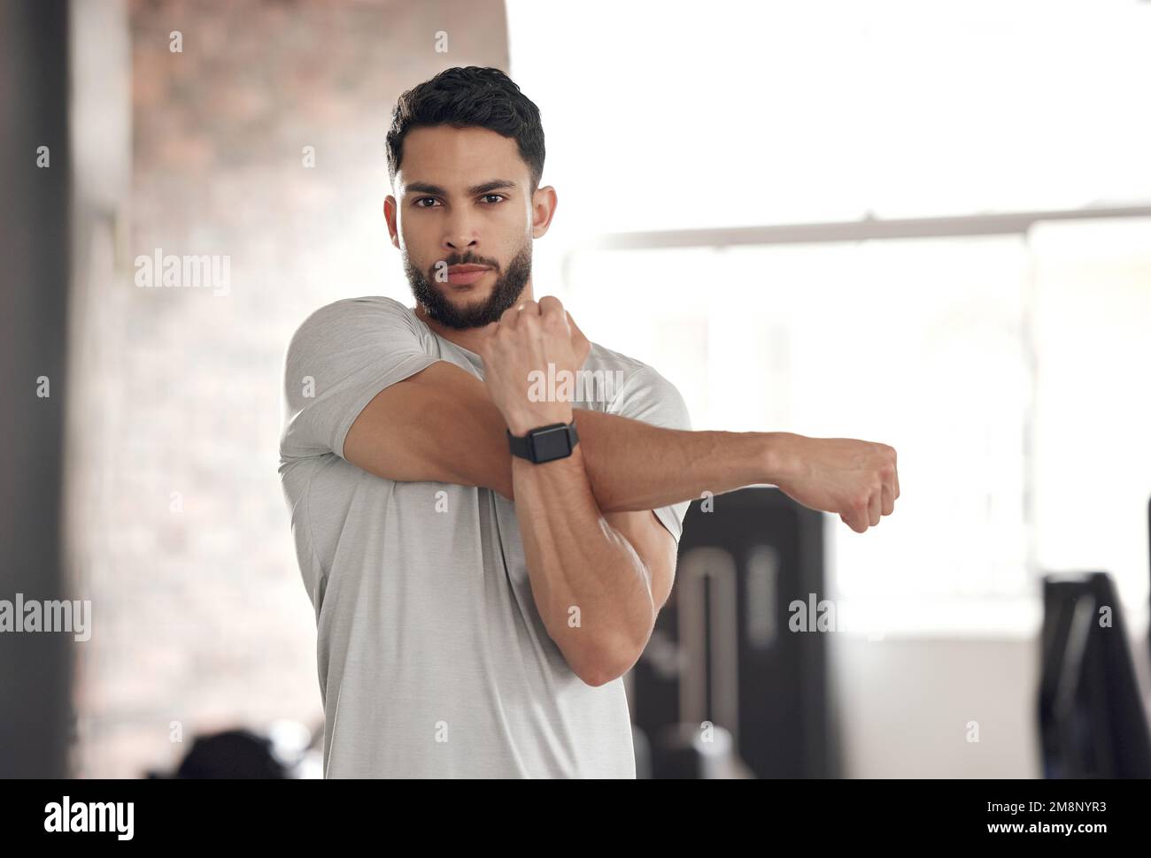 Portrait of one fit young hispanic man stretching arms and shoulders ...