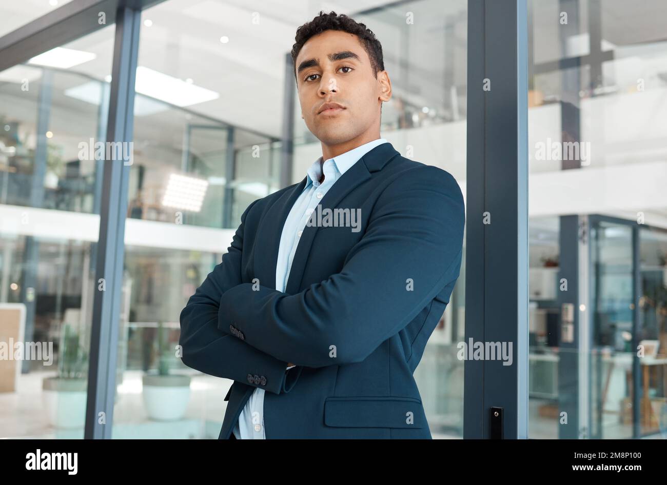 Young serious mixed race businessman standing with his arms crossed ...