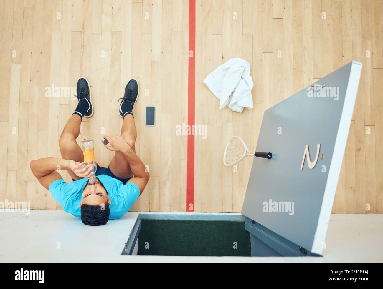 Above view of young athletic squash player sitting alone and drinking ...