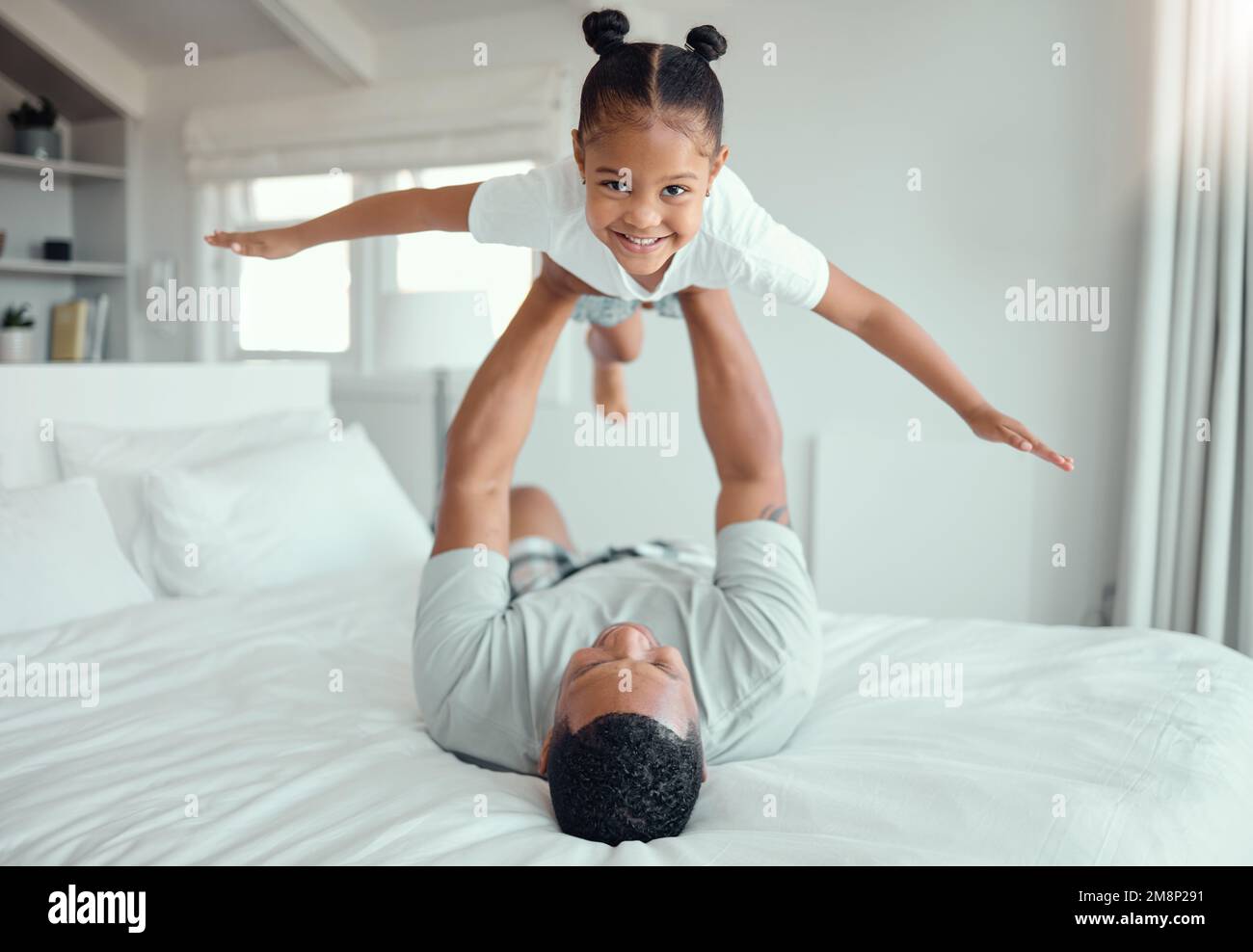 Happy little mixed race girl lying in fathers arms while looking at the ...