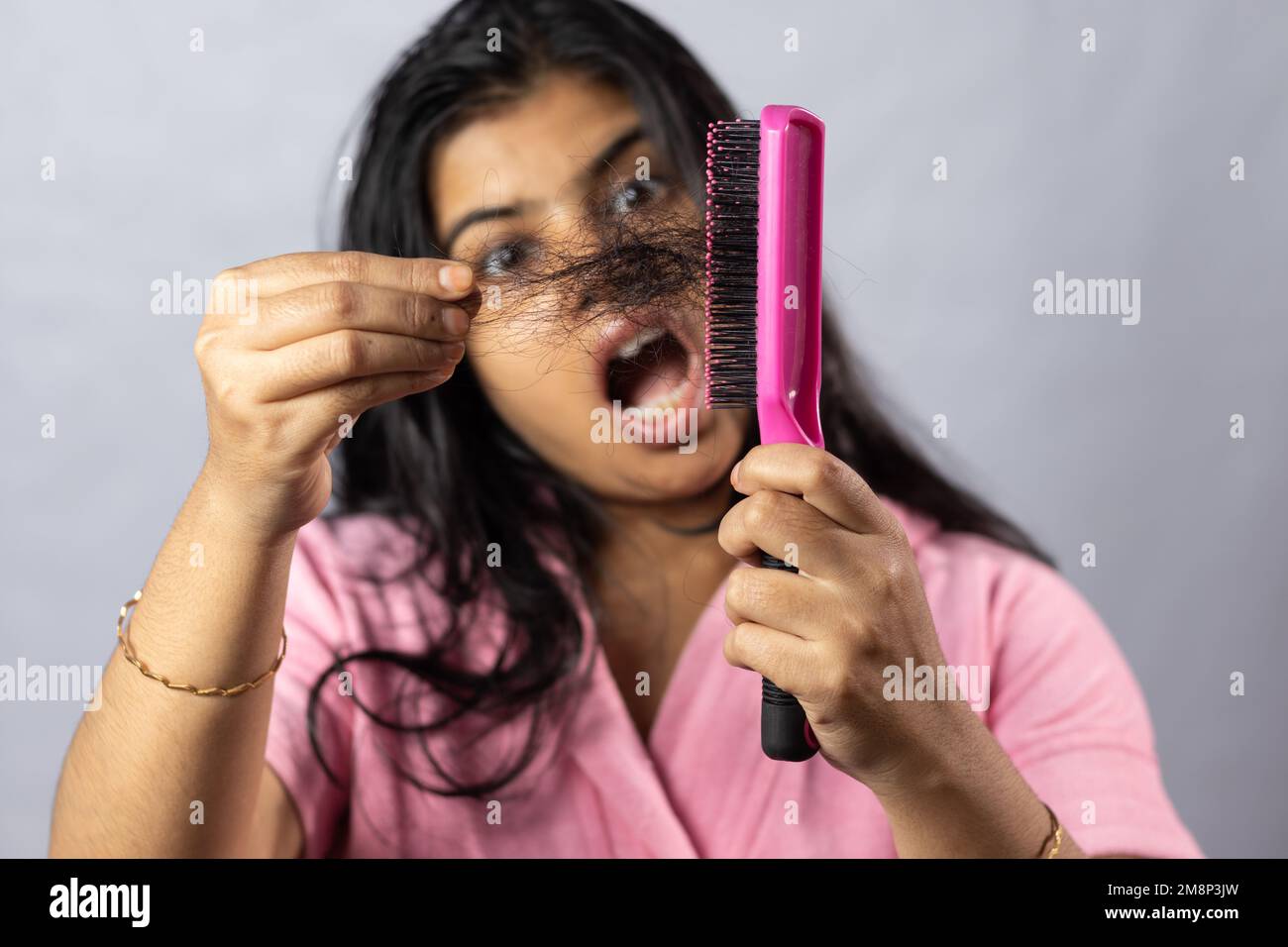 Selective focus on a pink hair brush full of fallen hair held in hand ...