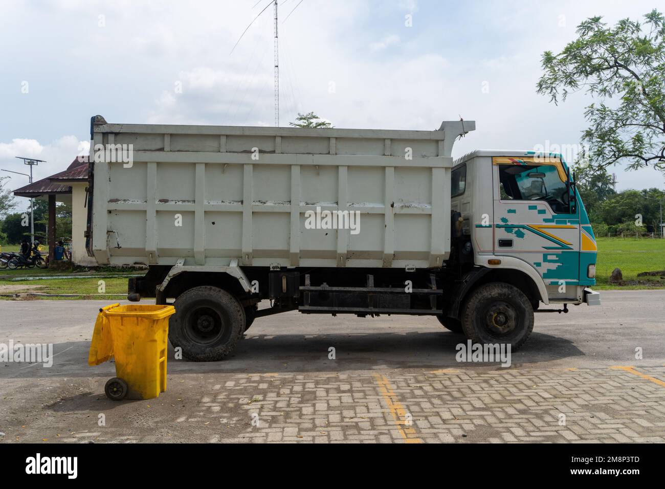 Logistics box truck is parked in city park near a yellow trash bin area ... Logistics box truck is parked in city park near a yellow trash bin area ...