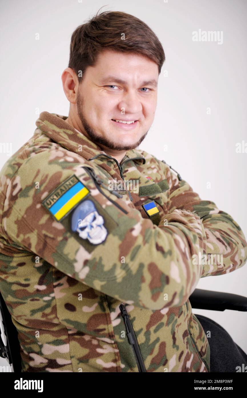 Happy positive young man in camouflage uniform soldier sitting in ...