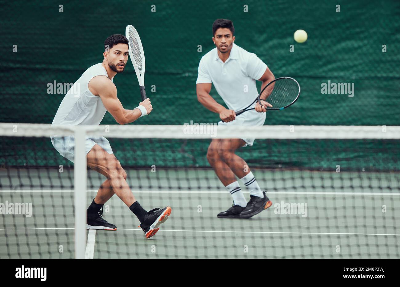 Two ethnic tennis players holding rackets and playing game on a court ...