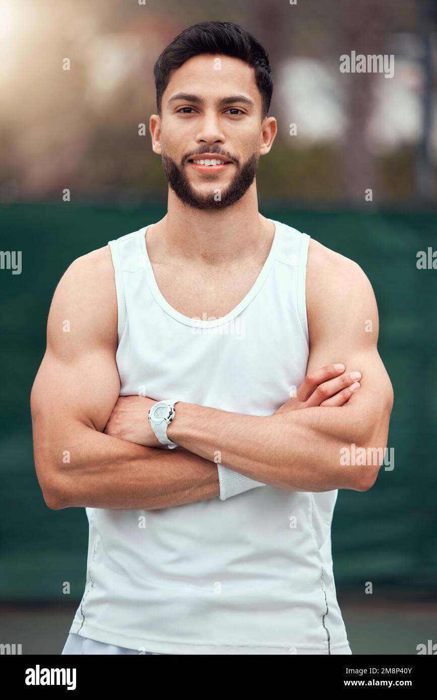 Portrait of smiling mixed race tennis player with arms folded and ...