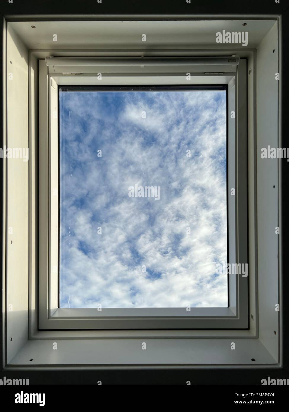 A vertical shot of view of the blue sky with windy clouds through white ...