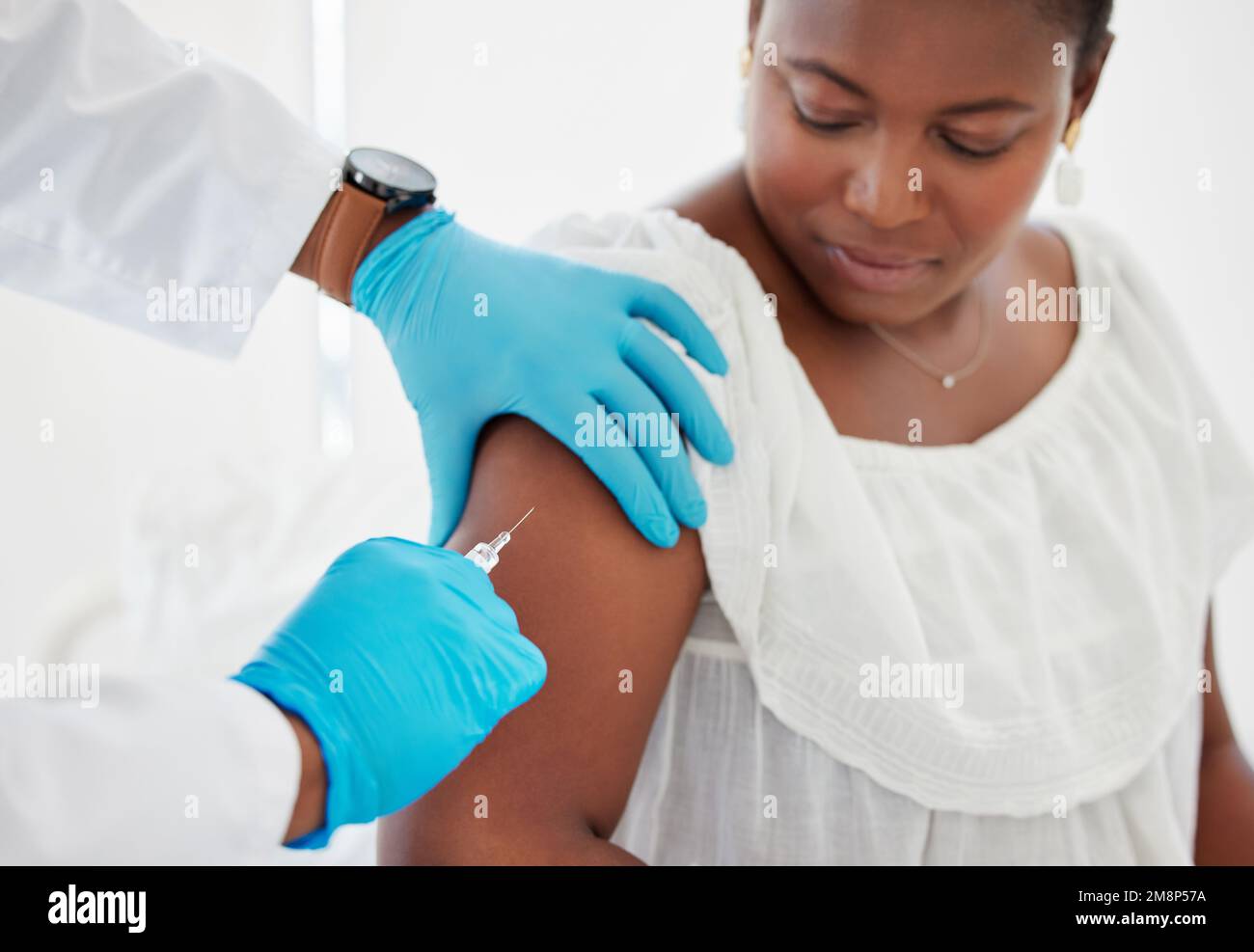 Doctor injecting a patient in the arm. Hand of a doctor injecting a ...