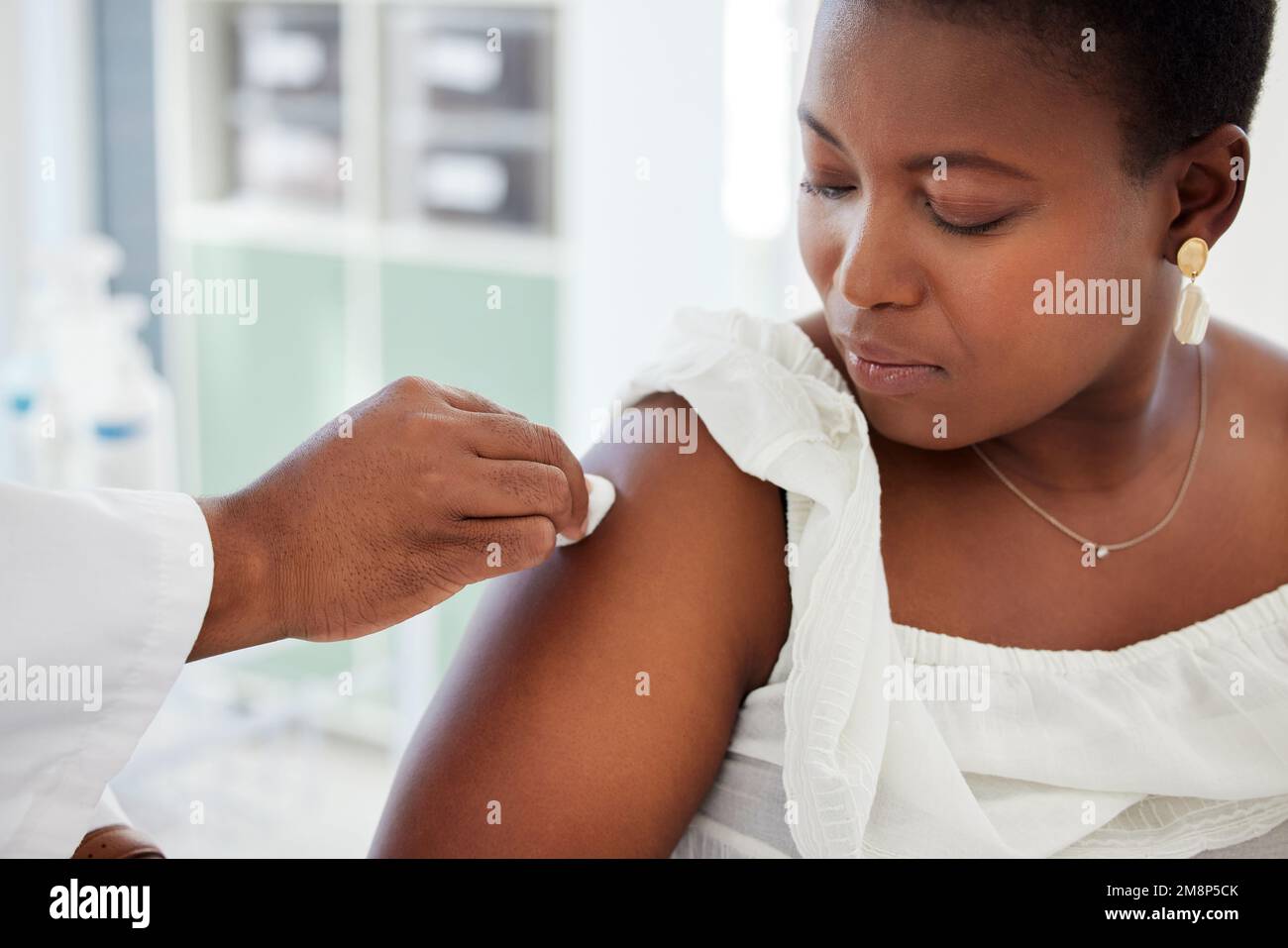 African american patient watching a doctor clean her arm. hand of a gp ...