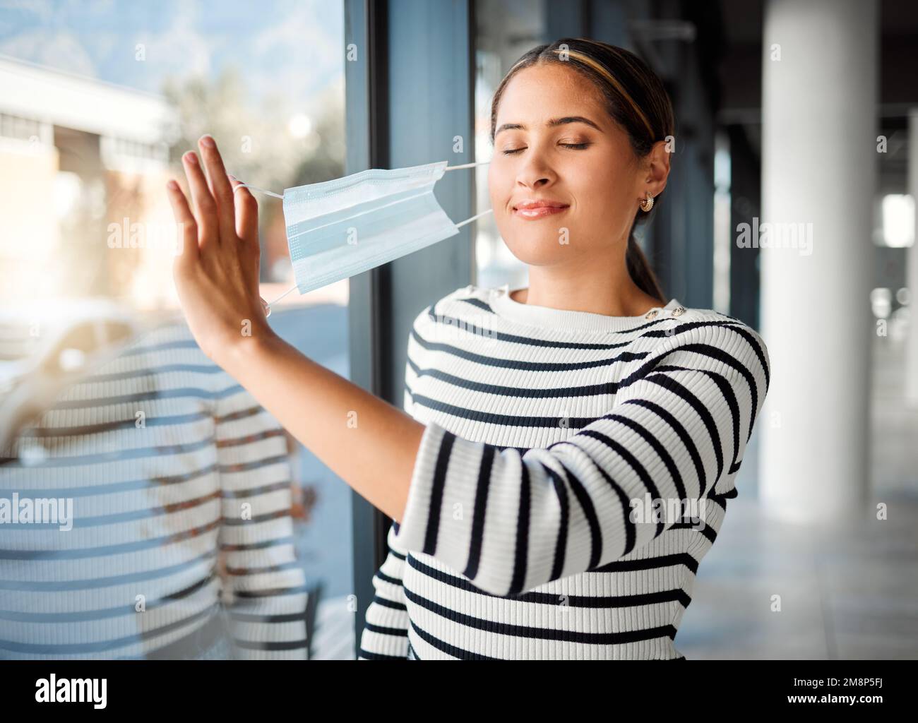 Young content mixed race businesswoman removing her mask while at work ...