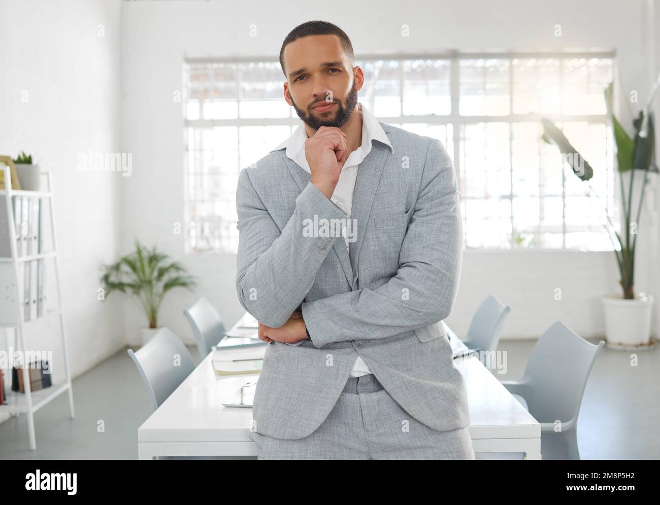 Young focused mixed race businessman standing in an office alone. One ...