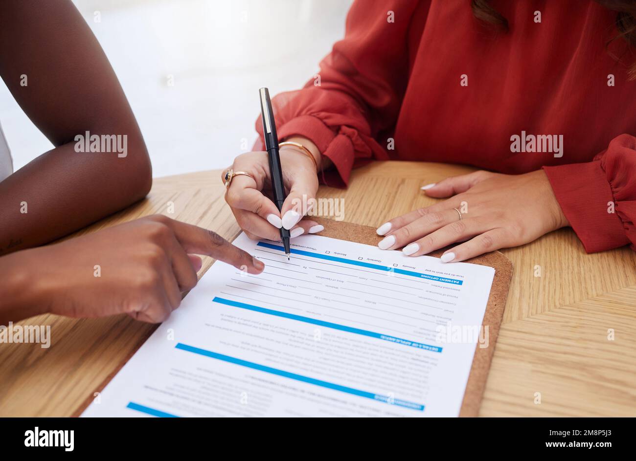 Closeup of two unknown ethnic business woman sitting and signing office ...