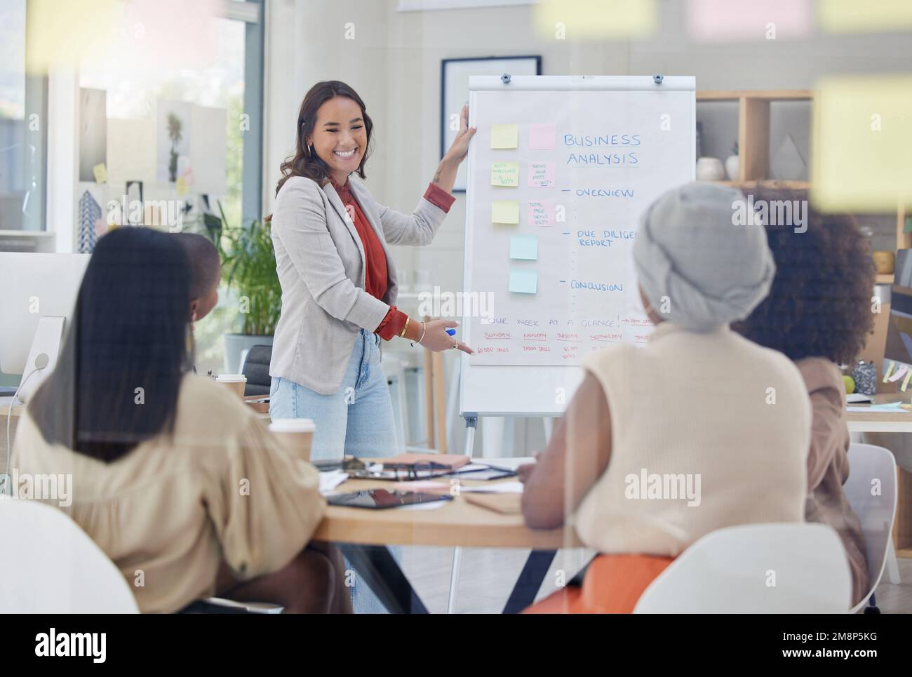 Ambitious asian business woman using a whiteboard for staff training in an office workshop ...