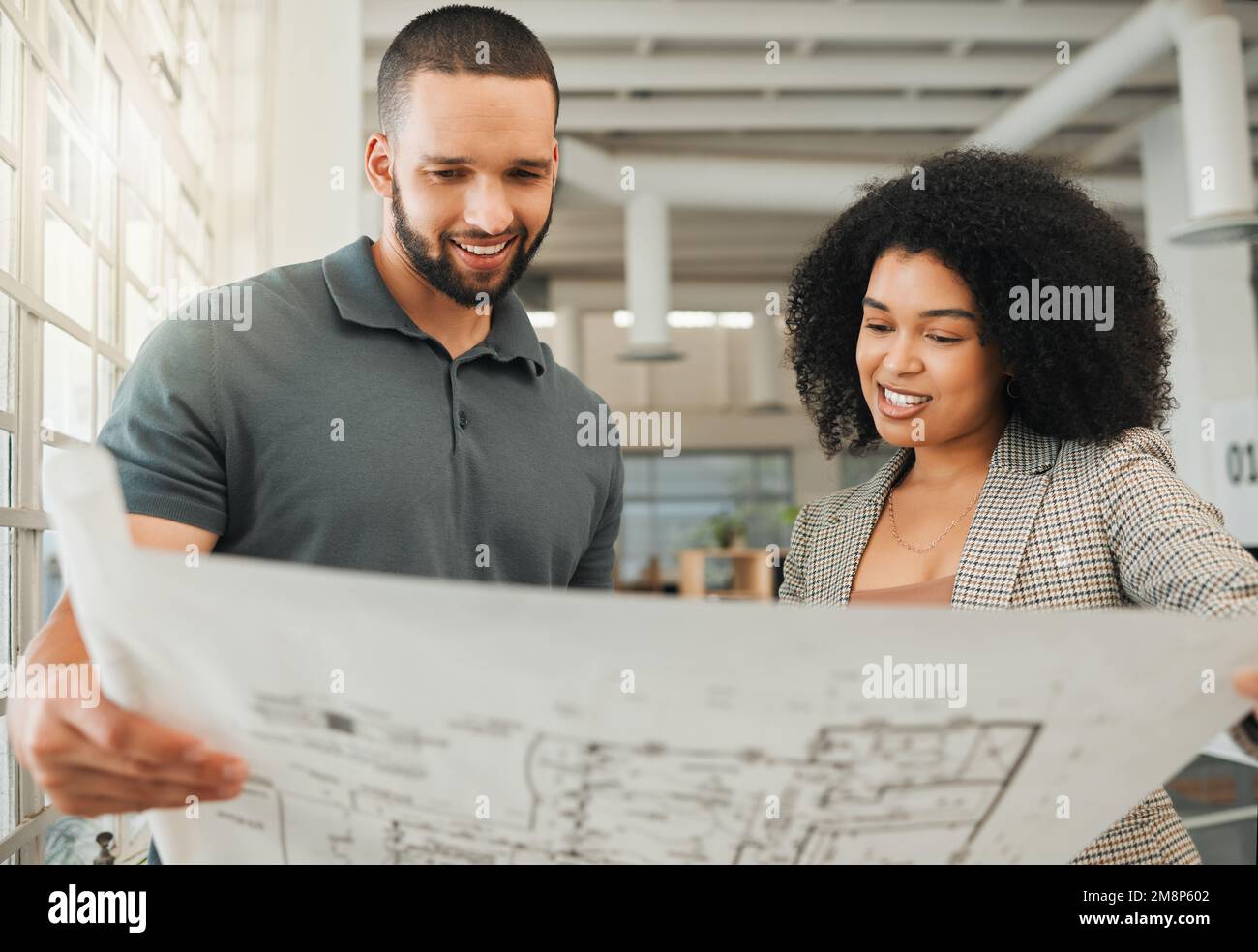 Young coworkers looking at a blueprint. Two businesspeople collaborate ...