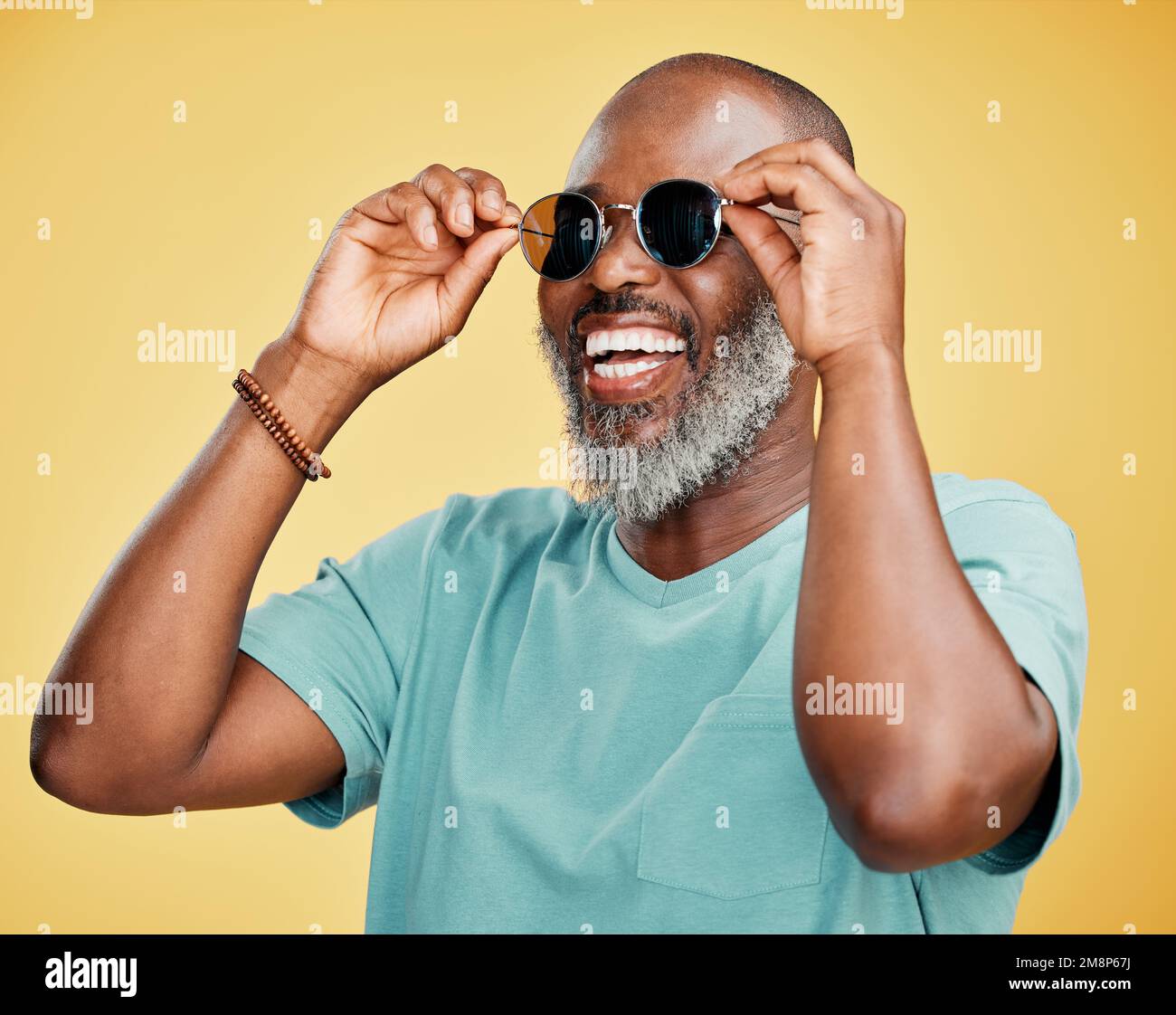 Happy mature African American man standing alone against yellow ...