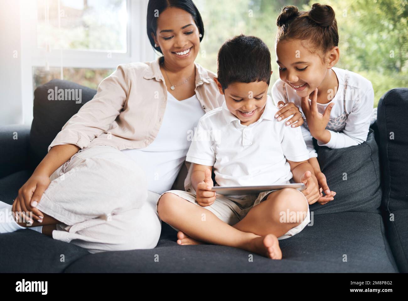 Happy young hispanic family sitting together and using tablet. Curious ...