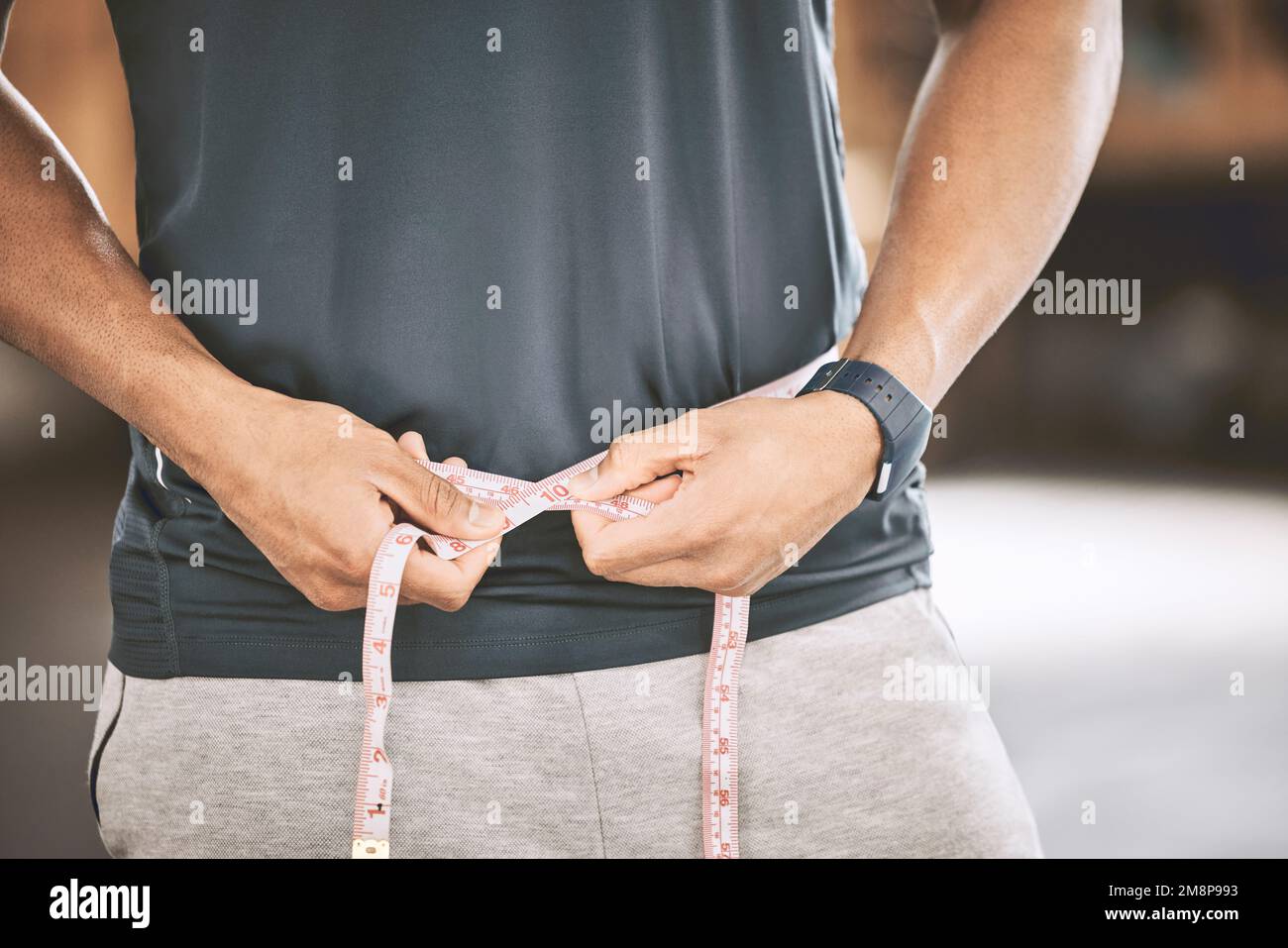 Hands of a bodybuilder measuring his waist. Fit trainer using tape ...