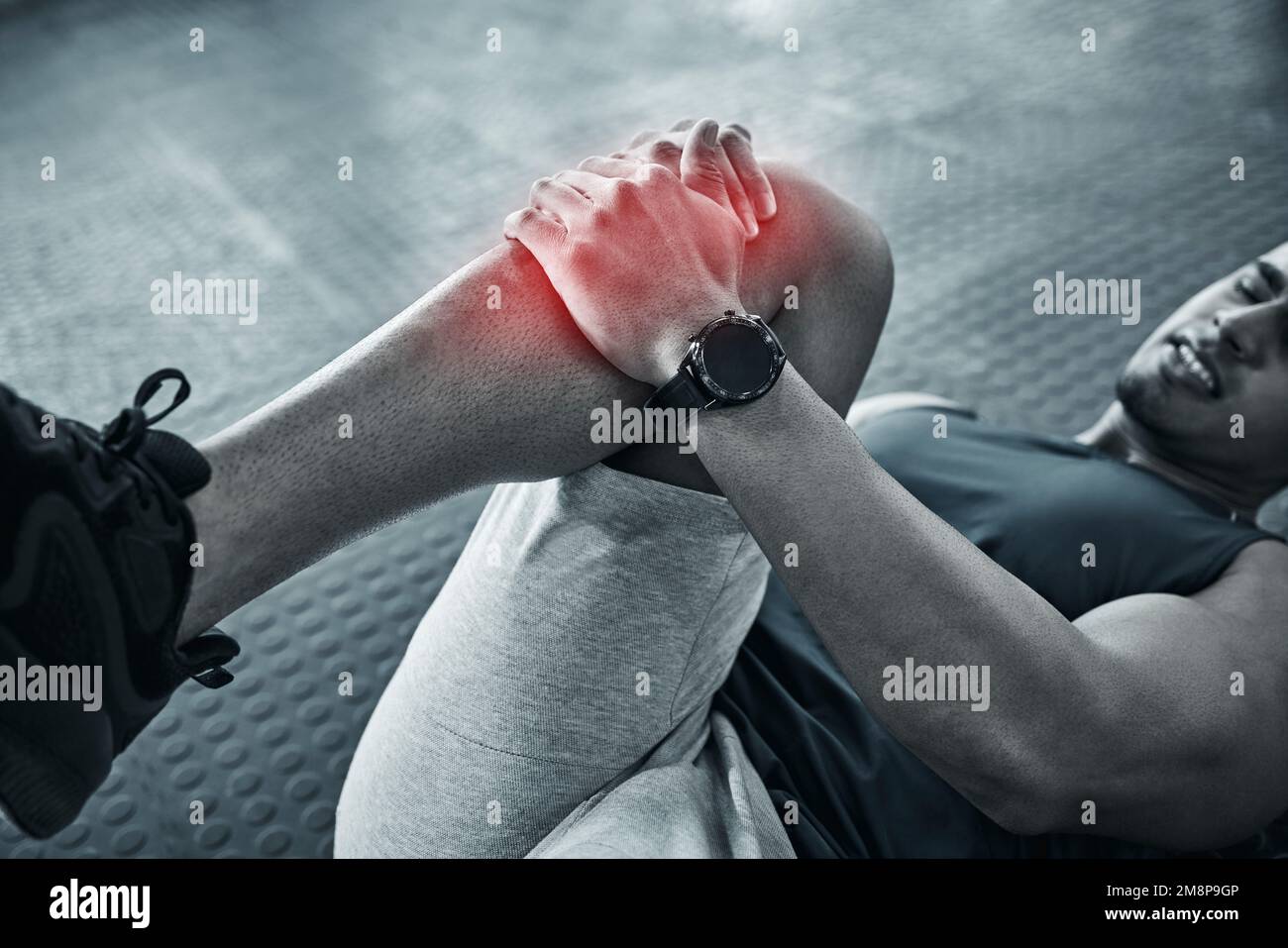 Young athlete in physical discomfort. Athlete lying on the floor with knee pain. Bodybuilder ...