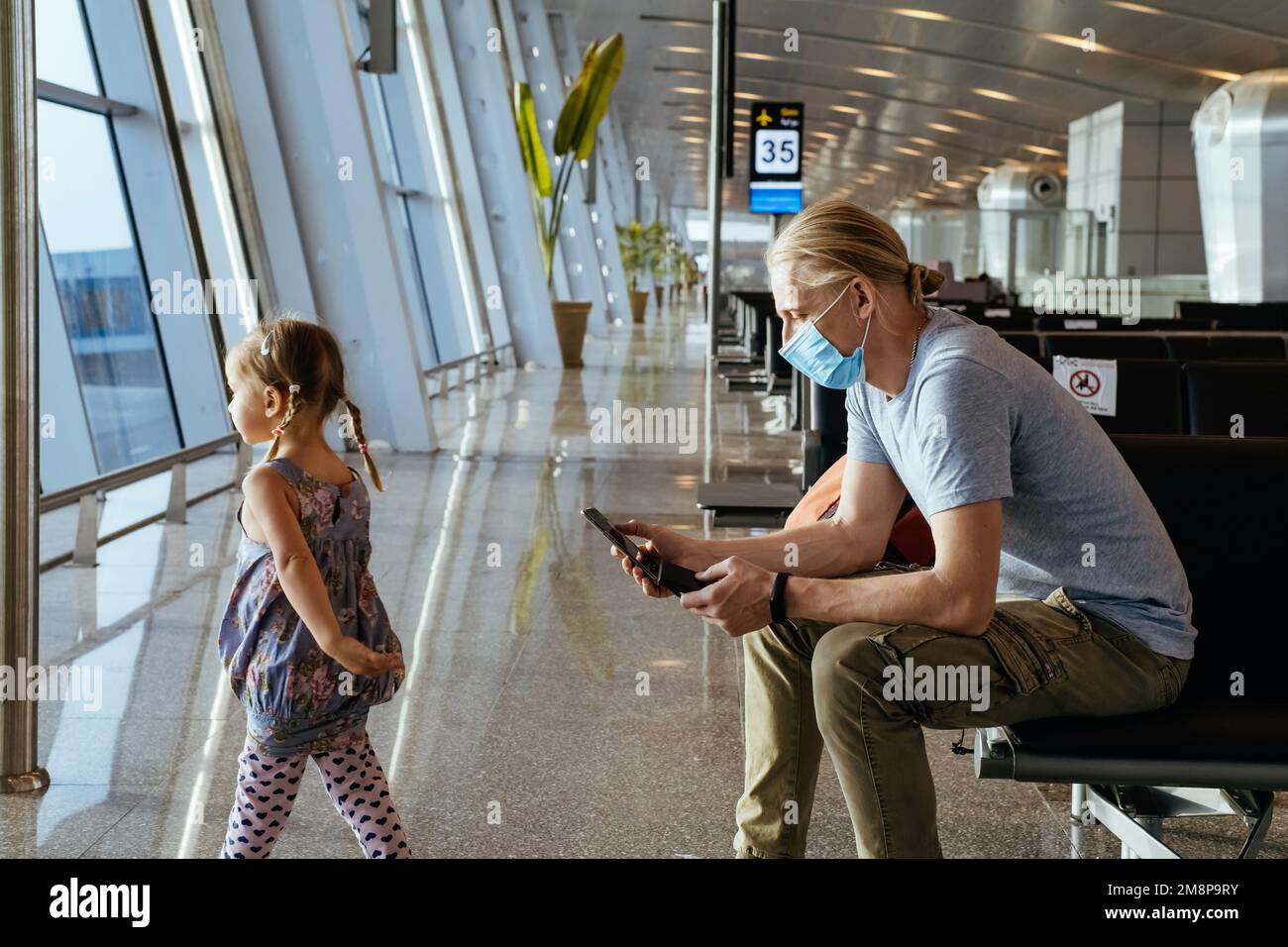 Man with girl ready to fly by airplane and the airport. Father looking ...